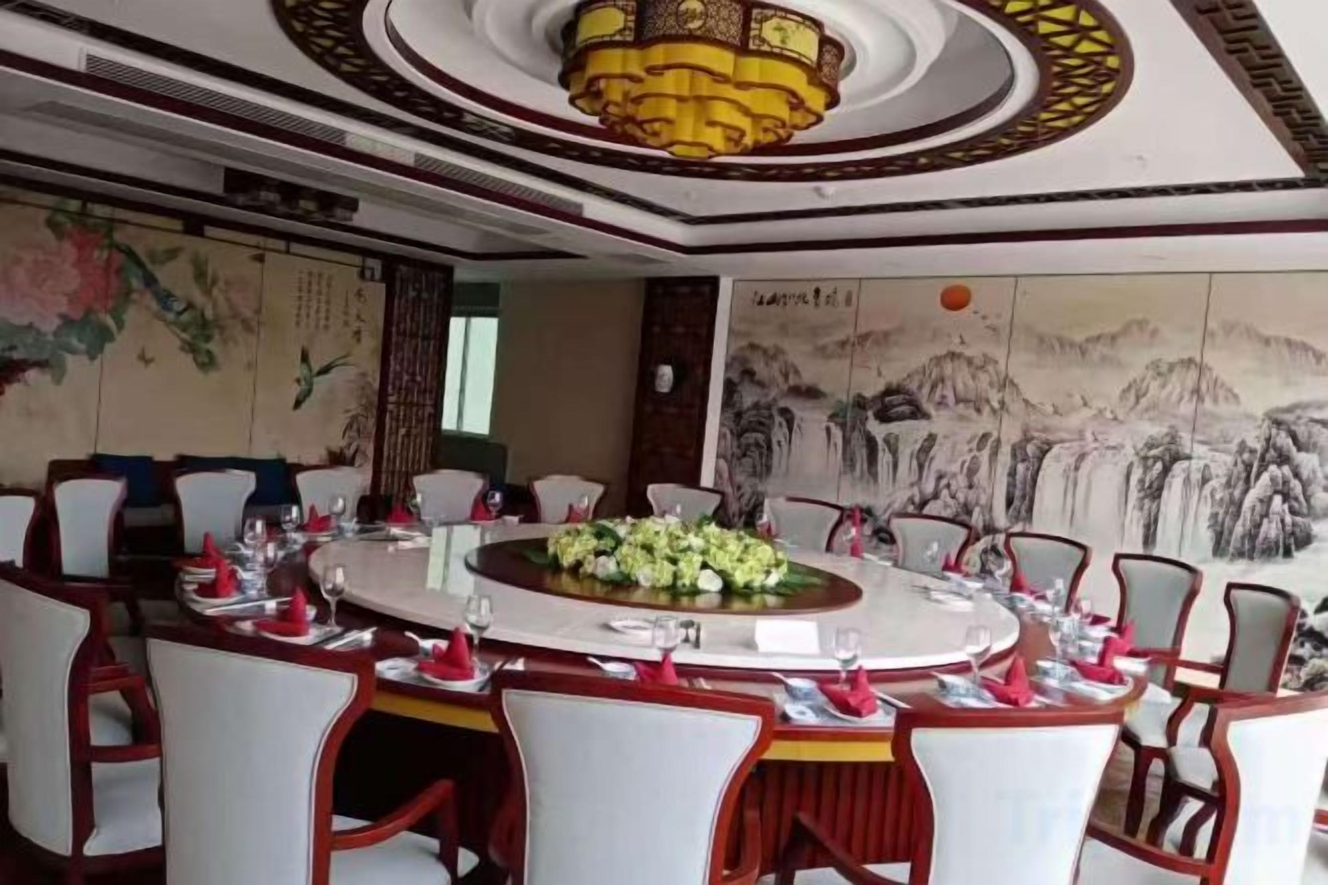 Sala de conferências com mesas redondas, cadeiras e um arranjo floral central.