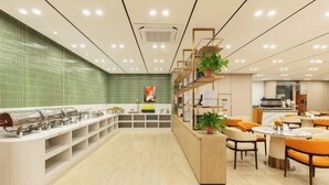 Um restaurante moderno com balcão extenso, área de estar e parede revestida de azulejos verdes.