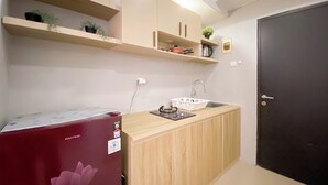 Uma cozinha compacta com geladeira, bancada de madeira e porta preta.