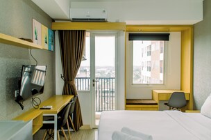Quarto de hotel com cama, escrivaninha com cadeira, televisão, janela com vista para edifícios e aparelho de ar condicionado.