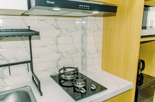 Uma cozinha com fogão a gás Rinnai, uma pia de aço inoxidável e painel de fundo de mármore.