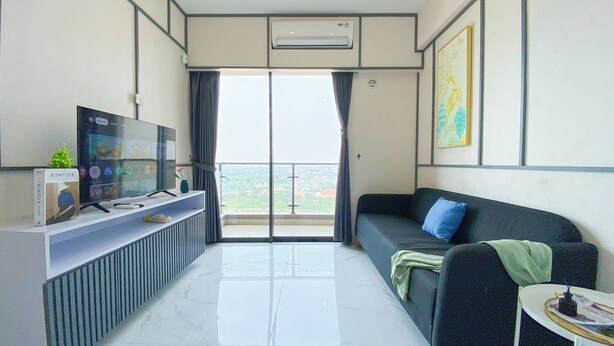 Uma sala de estar moderna com televisão de tela plana, um sofá, uma mesa pequena e uma varanda com vista.