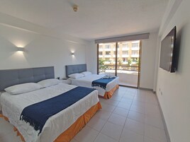 Quarto de hotel com duas camas, varanda e televisão fixada na parede.