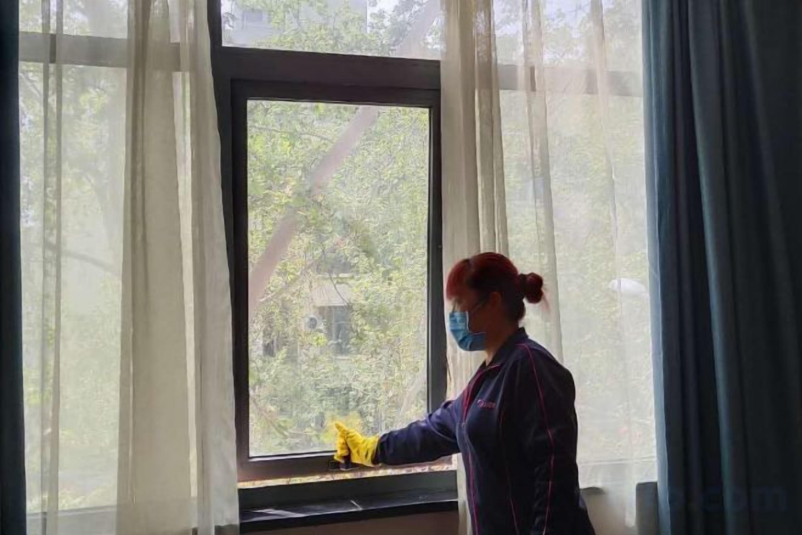 Uma pessoa limpando um vidro com um pano amarelo.