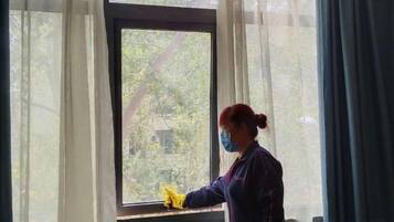 Uma pessoa limpando um vidro com um pano amarelo.