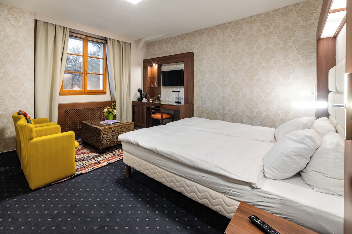 Quarto de hotel com uma cama, uma escrivaninha, uma cadeira e uma janela.