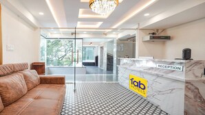 Uma área de recepção de hotel moderna, com um sofá de couro, balcão de recepção e porta de vidro que dá para um banheiro.