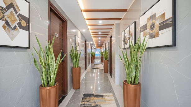 Um corredor moderno com pisos de mármore, portas de madeira e plantas em vasos.