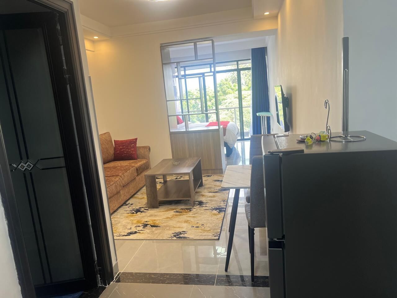 Uma sala de estar moderna com um sofá, mesa de centro e uma geladeira preta.