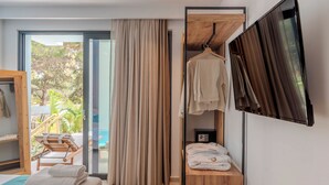 Quarto de hotel moderno com cama, um banco de madeira, televisão e vista para o exterior.
