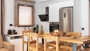 Cozinha moderna com área de refeições, incluindo uma mesa de madeira, cadeiras e uma geladeira.
