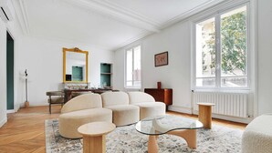 Uma sala de estar moderna com um conjunto de sofá, uma mesa de centro de vidro e uma grande janela com vista para o verde.