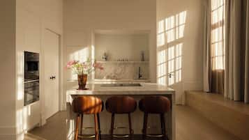 Cozinha moderna com bancada de mármore, forno embutido e um vaso com flores.