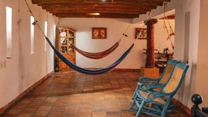 Quarto com rede, cadeiras de balanço azuis e piso de azulejos.