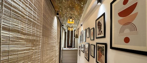 Um corredor com parede de bambu, obra de arte emoldurada e luminária decorativa.