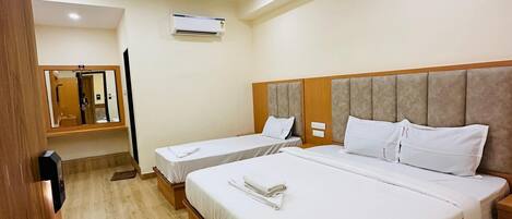 Quarto de hotel com duas camas, piso de madeira, ventilador de teto e ar condicionado.