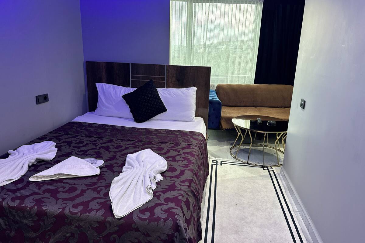 Quarto de hotel com cama, sofá, mesa de centro e banheiro.