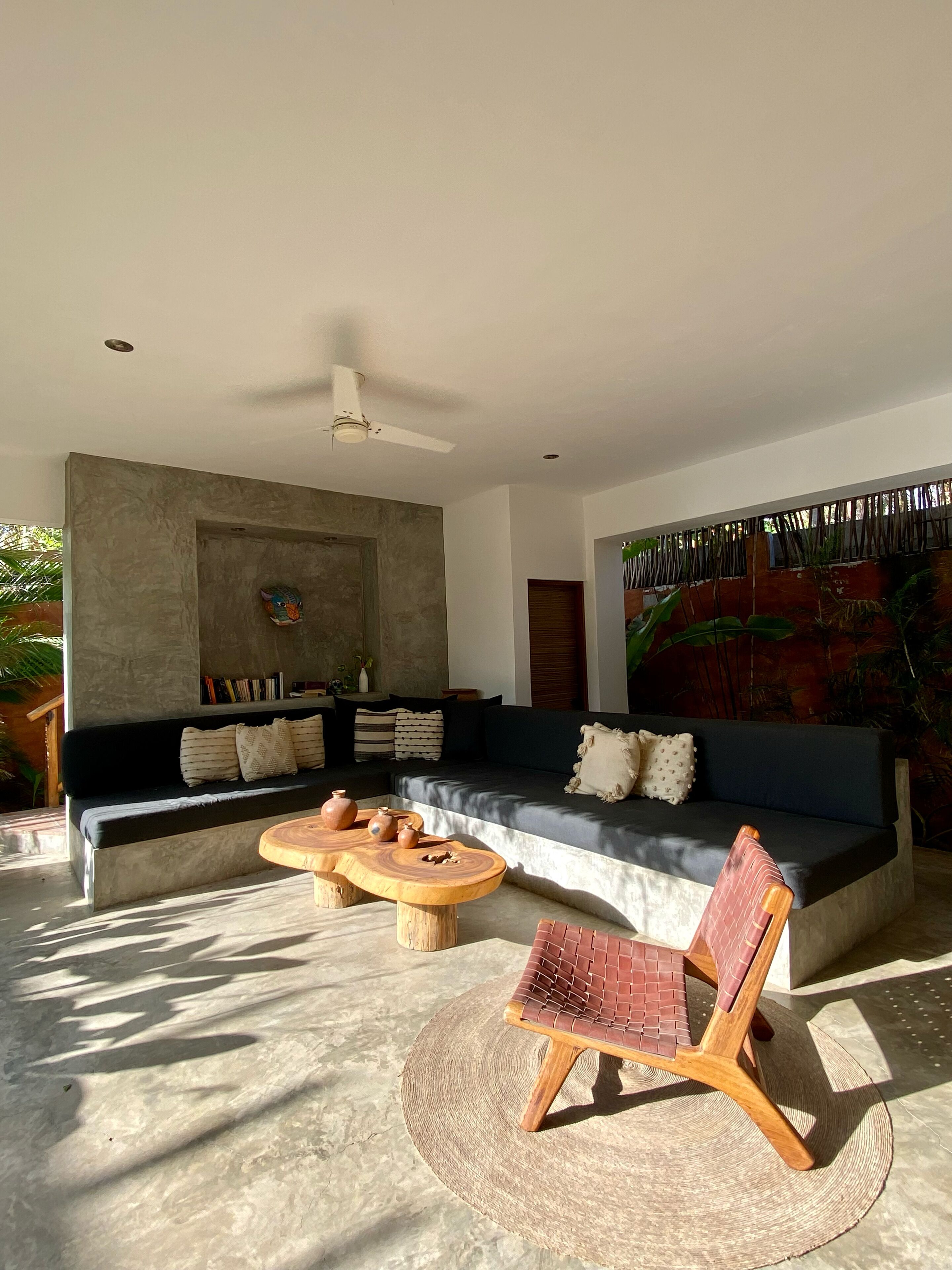 Uma sala de estar moderna com um sofá, uma mesa de centro de madeira e uma poltrona de fibra natural.