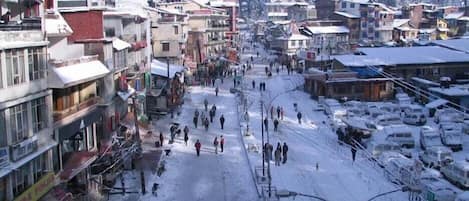 Cena de rua coberta de neve, com edifícios e carros estacionados.