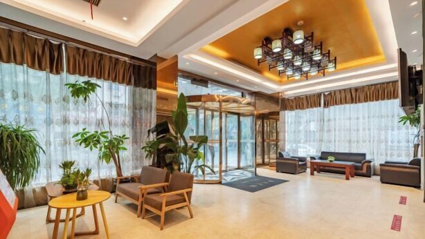 Um hall de hotel moderno com uma porta giratória, área de estar e grandes janelas.