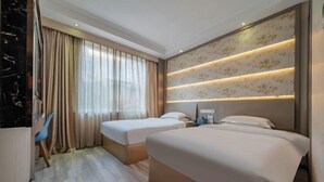 Quarto de hotel com duas camas, uma escrivaninha e uma cadeira.