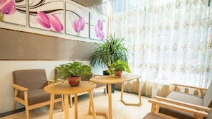 Um quarto acolhedor com duas cadeiras de madeira, uma mesa redonda pequena e duas plantas em vasos.