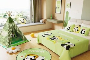 Quarto infantil com cama, um assento junto à janela, um tipi verde e decoração com tema de panda.