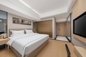 Quarto de hotel moderno com uma cama grande, mesas de cabeceira, televisão de tela plana e um espelho amplo.