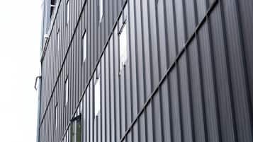Um edifício moderno com fachada vertical em ripas e várias janelas.