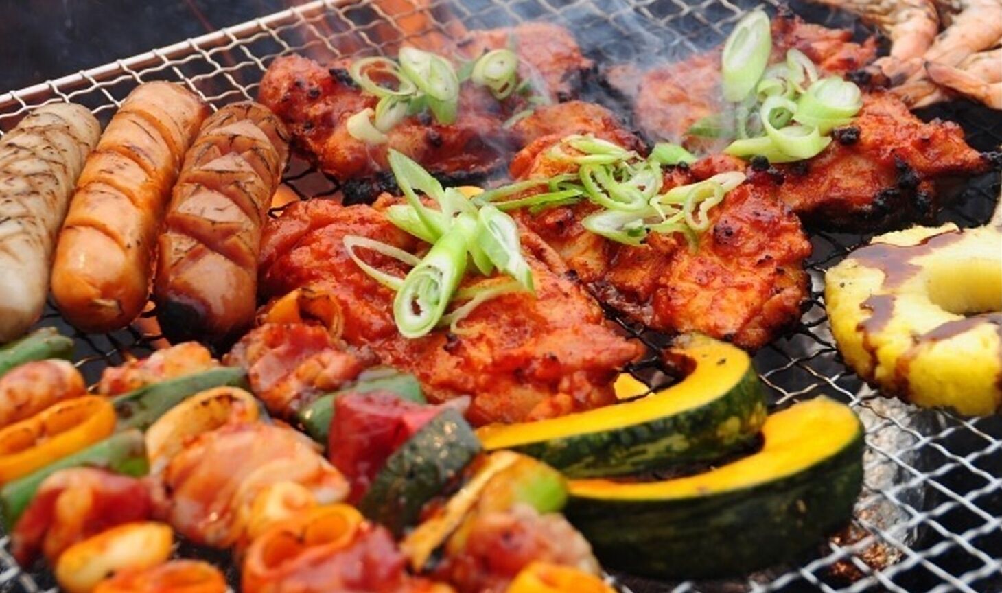 Diversos cortes de carne grelhada e legumes na churrasqueira.