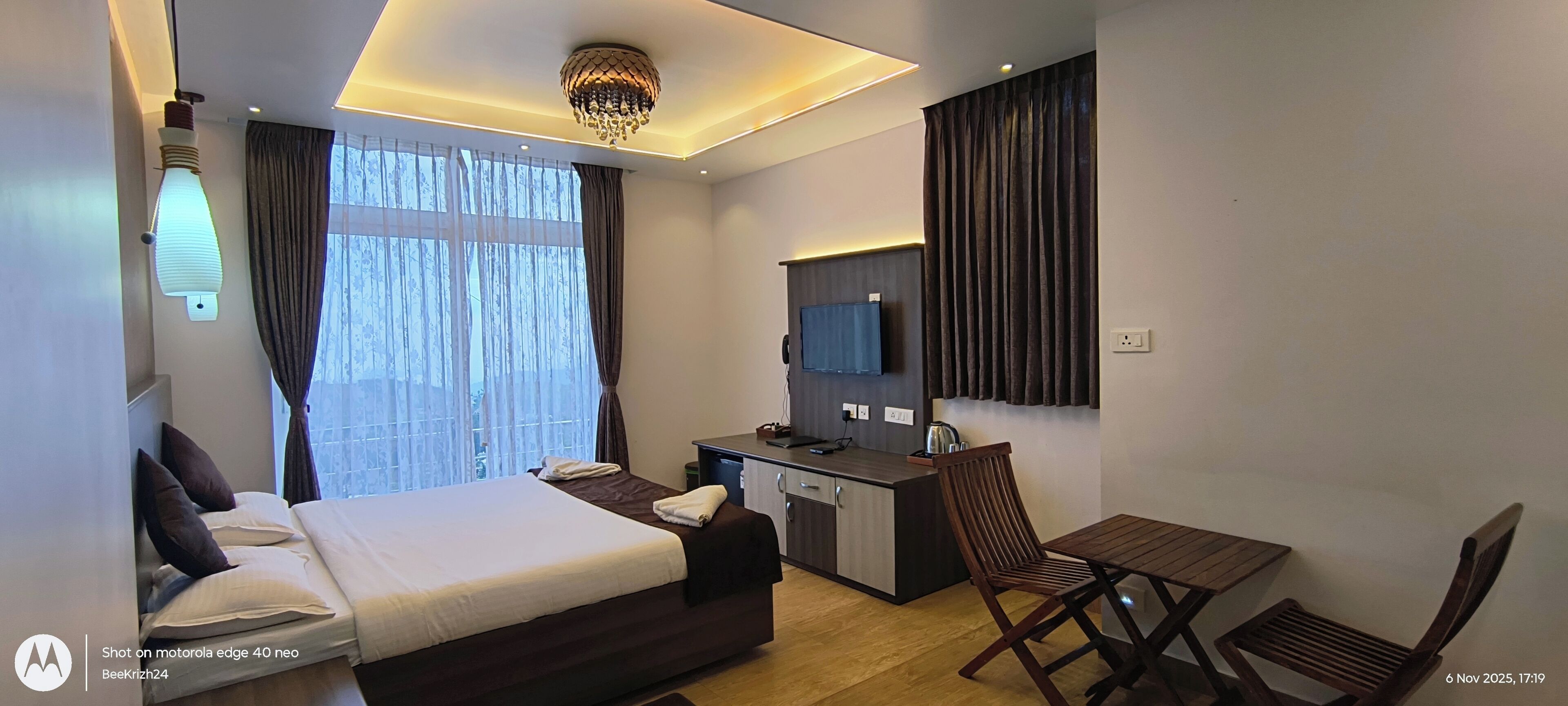 Quarto de hotel moderno com cama, escrivaninha e área de estar.
