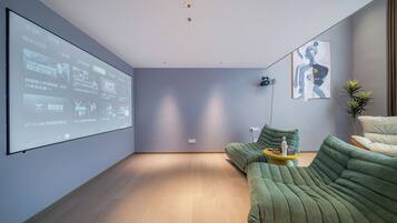 Uma sala de estar moderna com uma tela grande exibindo informações, um sofá verde, uma mesa redonda pequena e um quadro na parede.