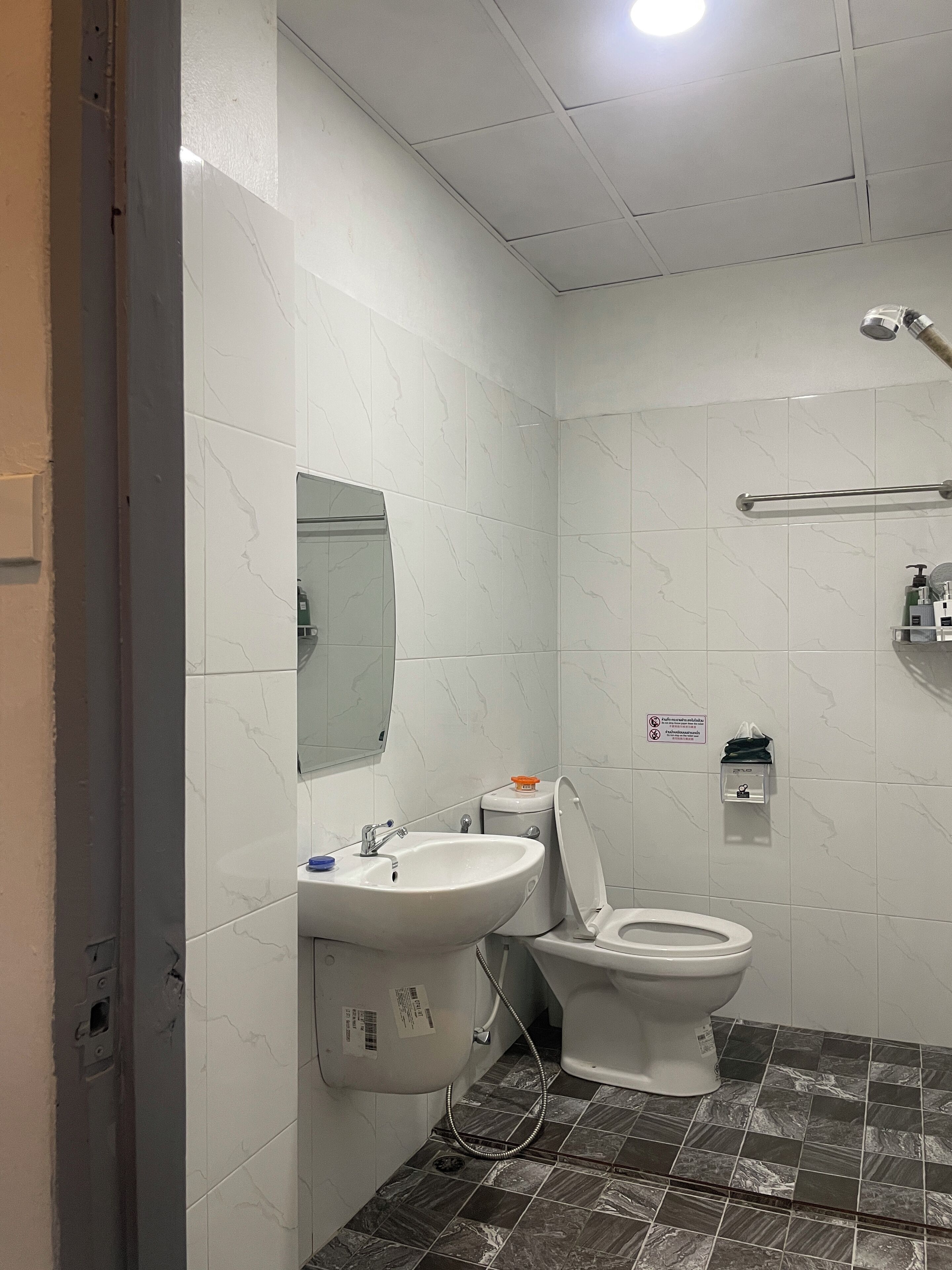 Um banheiro com azulejos de mármore branco, pia, vaso sanitário e chuveiro.