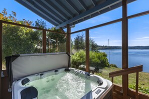 Uma banheira de hidromassagem com vista para um lago e vegetação ao redor.