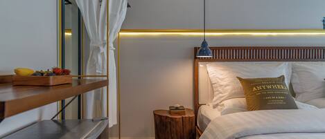 Quarto de hotel com cama, mesa de cabeceira e espelho.