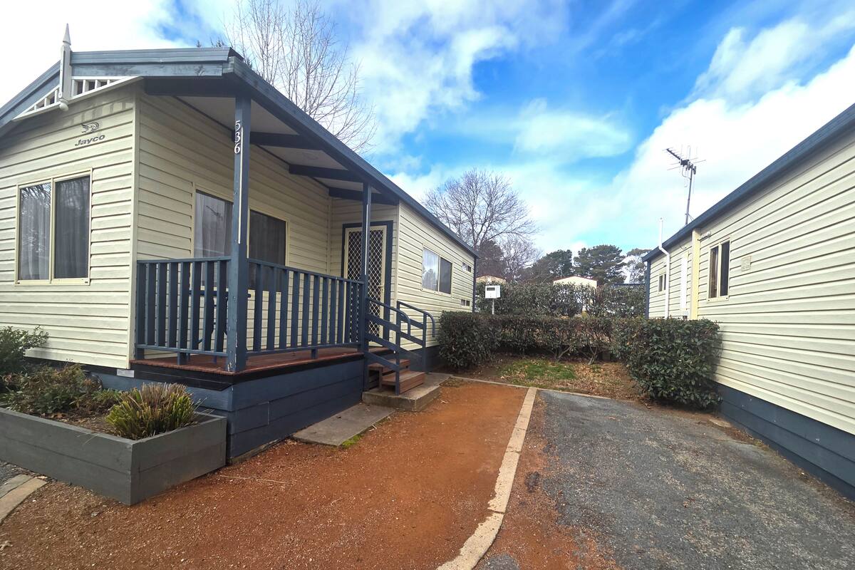 Uma casa móvel térrea com varanda e um pequeno jardim frontal.