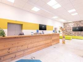 Uma área de recepção com balcão de madeira, parede de pedra e esquema de cores amarelo e branco.