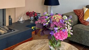 Uma sala de estar com uma mesa redonda, um vaso de flores, um abajur e um sofá.