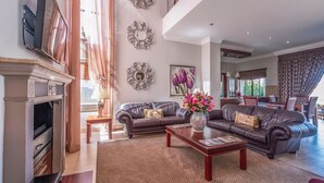 Uma sala de estar espaçosa com lareira, dois sofás, uma mesa de centro e espelhos decorativos.