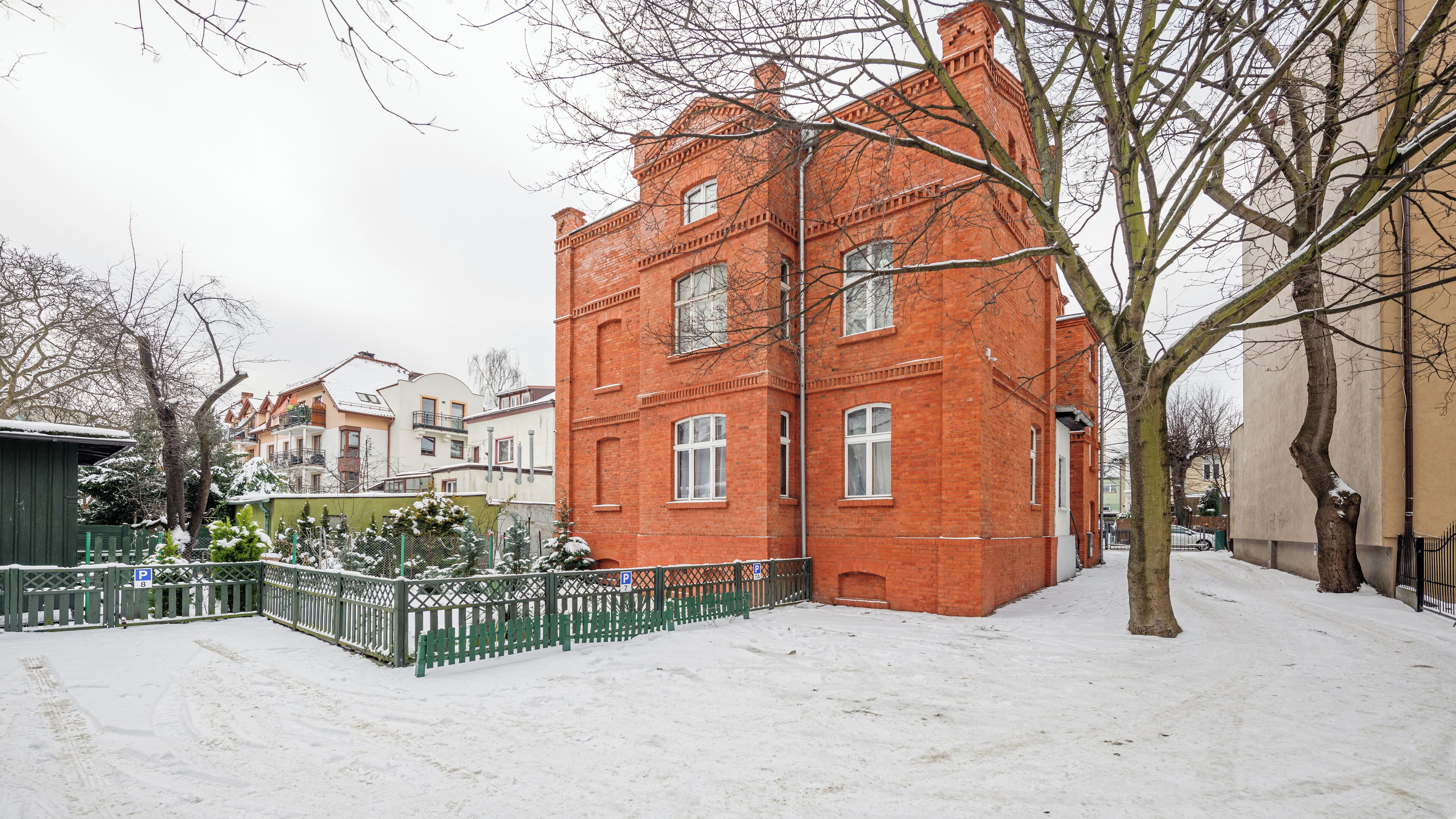 Um edifício de tijolos vermelhos com várias janelas e o chão coberto de neve.