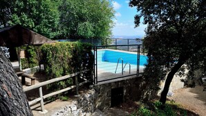 Uma área de piscina com paredes de pedra, um deck de madeira e um espaço coberto para sentar.