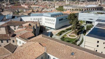 Um edifício moderno com fachada geométrica distinta, cercado por construções tradicionais.