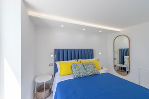 Um quarto moderno com cabeceira azul, um espelho redondo e uma mesinha de cabeceira.