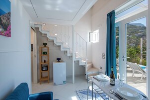 Interior moderno com escada, área de jantar com mesa e cadeiras, e vista para o exterior.