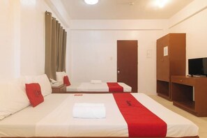 Quarto de hotel com duas camas, televisão, secretária e guarda-roupa.