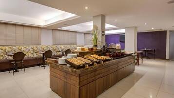 Uma área de refeições moderna com ilha central para buffet, disposição de assentos e uma planta decorativa.