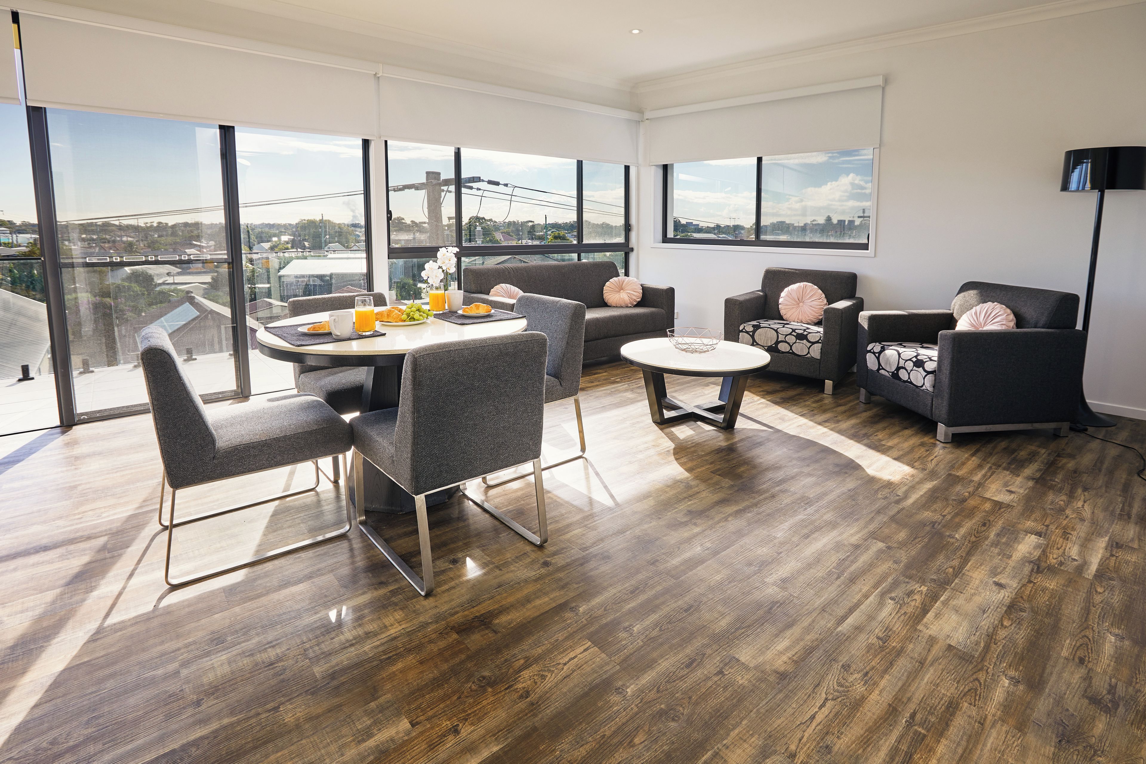 Uma sala de estar moderna com área de jantar, janelas amplas e vista para a cidade.