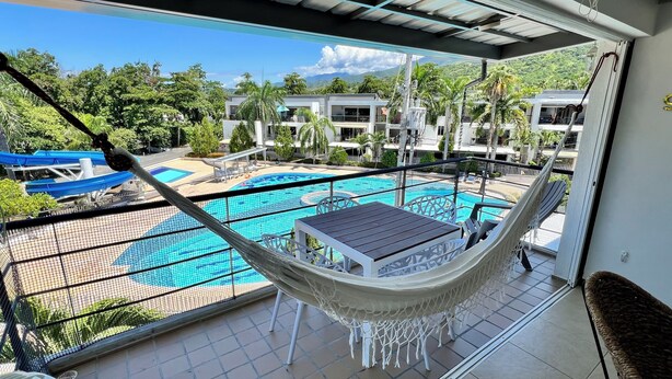 Uma rede numa varanda com vista para uma piscina e para a área do resort.