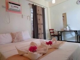 Quarto de hotel com cama, escrivaninha e cadeira.