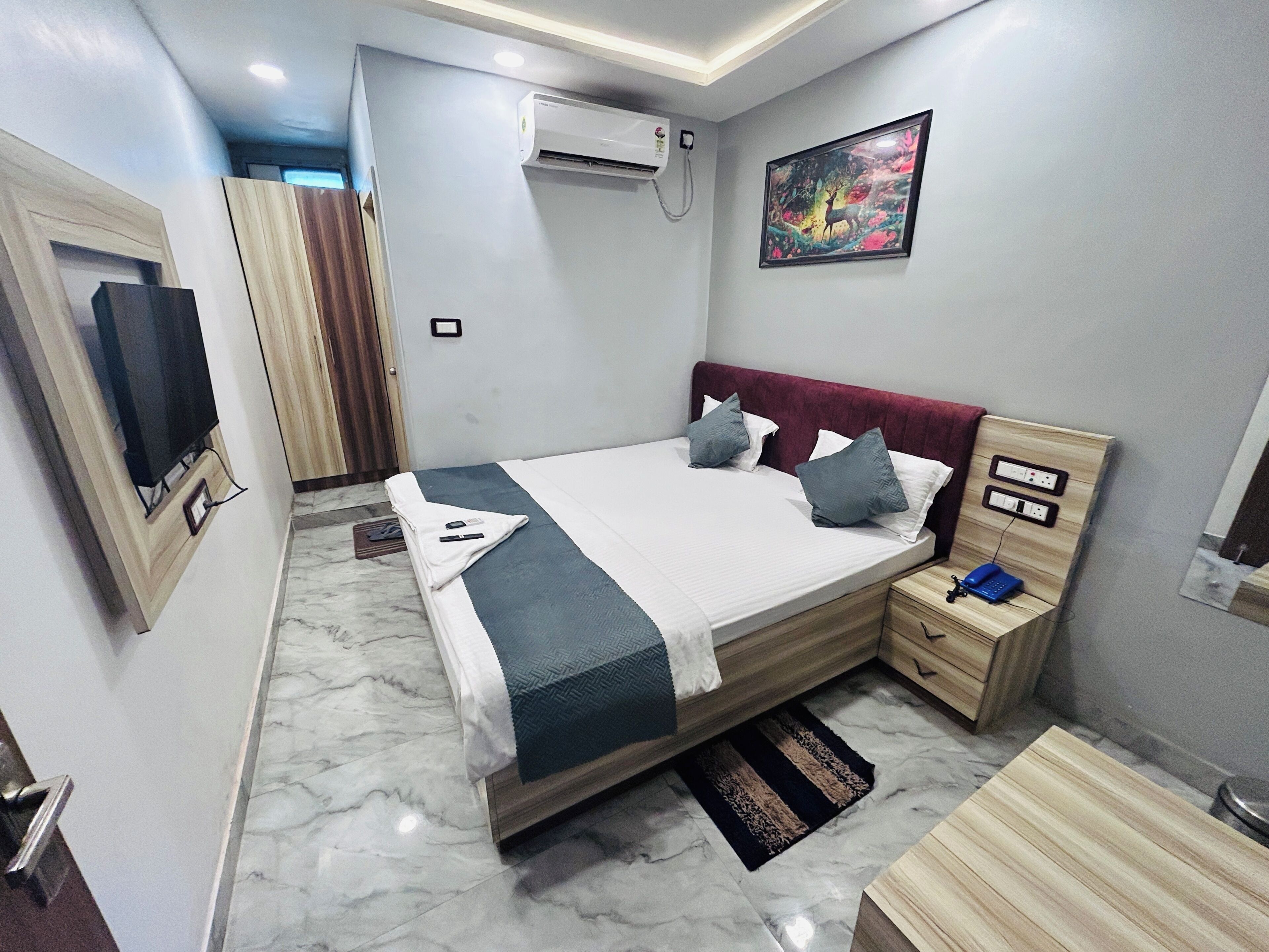 Quarto de hotel com cama, mesa de cabeceira, ar condicionado e um quadro na parede.